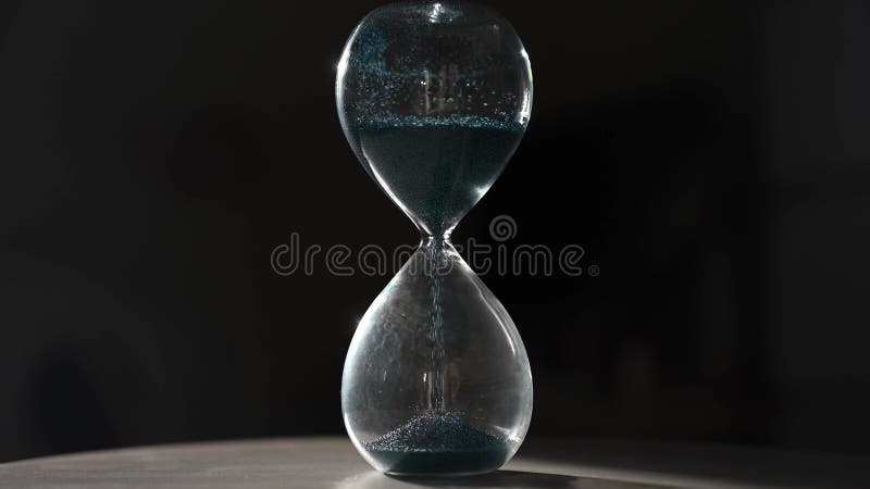 Hourglass with Blue Granules Spinning on a Black Background. Stock ...