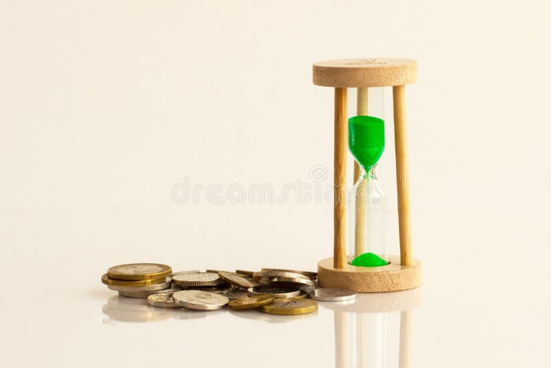 Hourglass with Coins on Table on Yellow Background Stock Image - Image ...