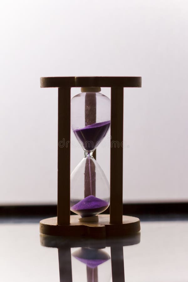A Pink Hourglass with Green Walls on a Brown Board with Coins and ...