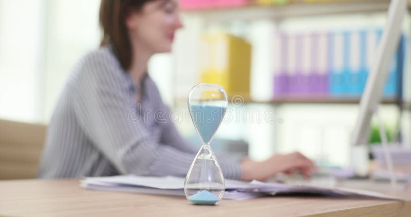 Hourglass is on Table in Office and Manager is Working at Computer ...
