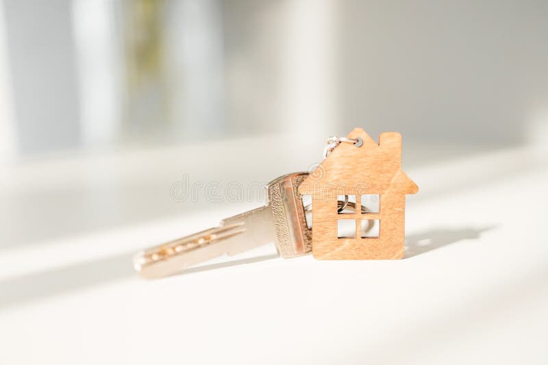 A House Key with a Keychain in the Form of a Wooden House on a Light ...