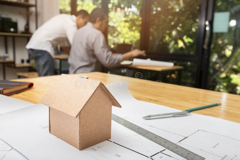 House Model on Desk Over Confident Team of Architects Working Together ...