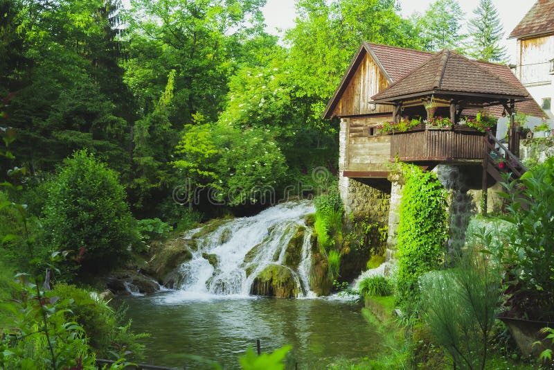 House with a Small Waterfall Pouring Down To River Surrounded by Trees ...