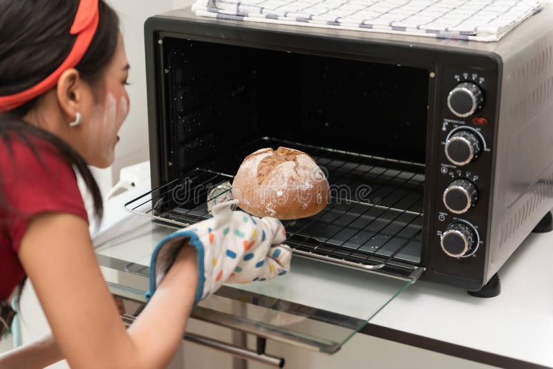 Housewife Taking Bread Out of Oven in Kitchen. View from Inside of the ...