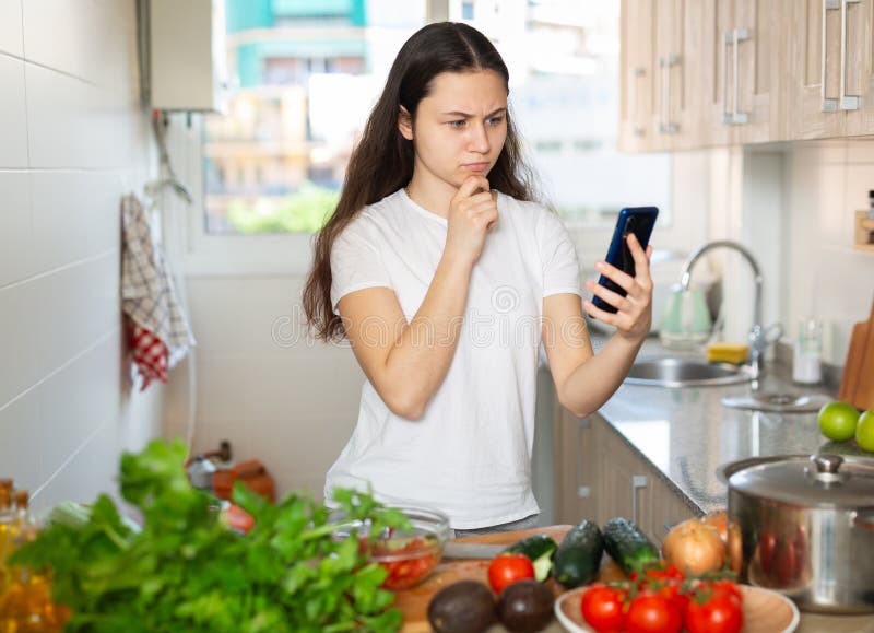 Housewife Using Mobile Phone during Cooking at Kitchen Stock Photo ...