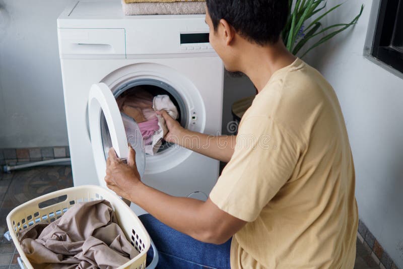 Housework. Asian Man Loading Clothes into Washing Machine Stock Photo ...