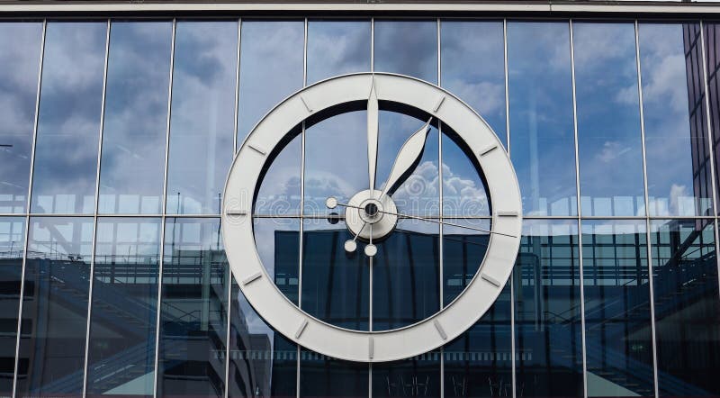 A Huge Clock on a Glass Facade with a Reflection of the Blue Sky and ...
