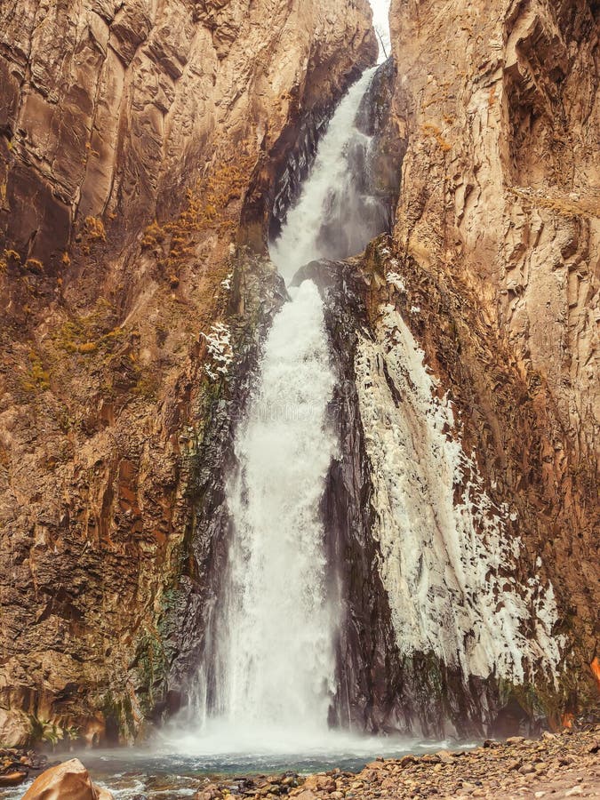 A Huge Powerful Waterfall Flows Down between the Steep Cliffs of the ...