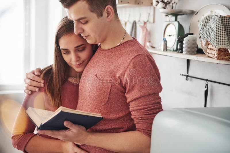 Hugs Each Other Cute Couple Reading Book Together At Home In The