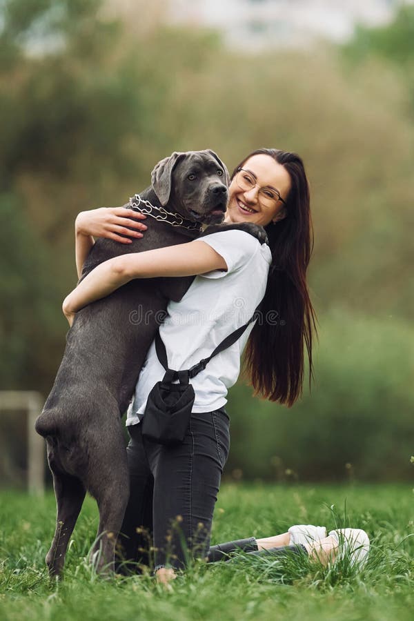 Hugs the Pet. Young Brunette is Having a Walk with Her Dog Outdoors ...