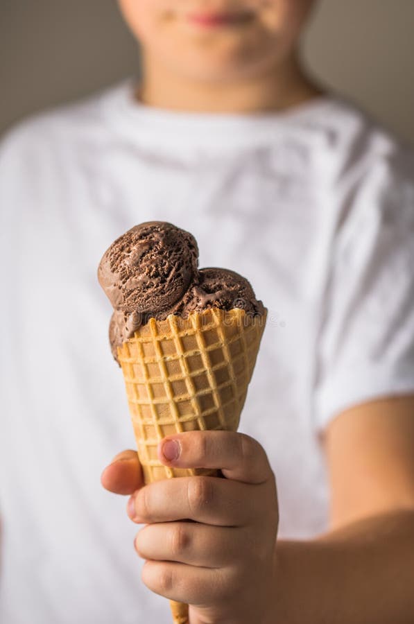 A Human Hand Holds a Ice Cream Cone Up. Nine Year Boy Eating Ice Cream ...