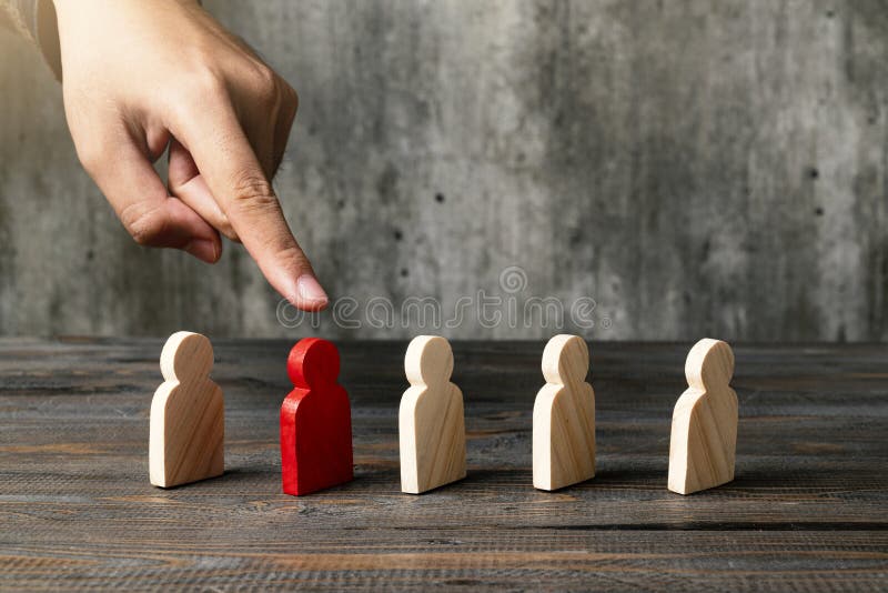 A Human Hand Pointing To One Wooden Figure from the Row of Wooden ...