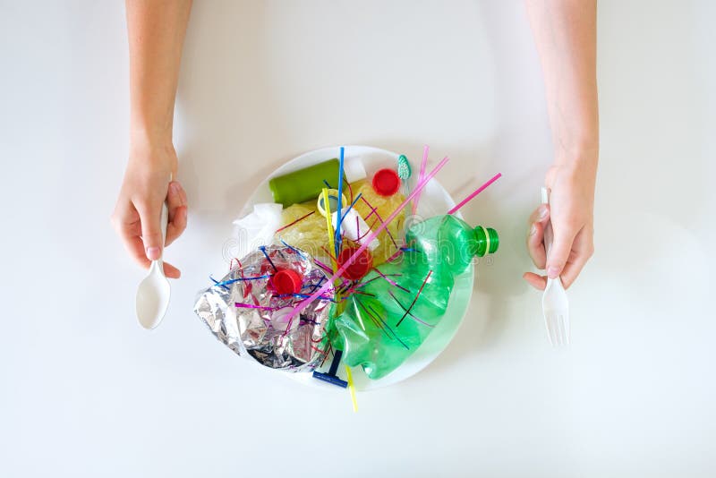 Human Hands Hold a Fork and Spoon Over a Plate of Plastic Trash. Stock ...