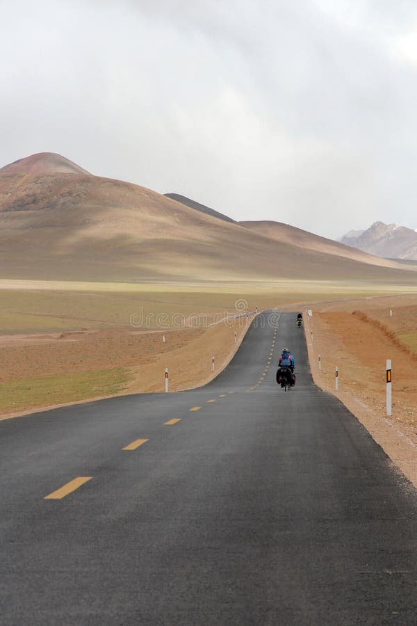 Human Riding Bicycle on Road through Desert Surrounded by Mountains ...