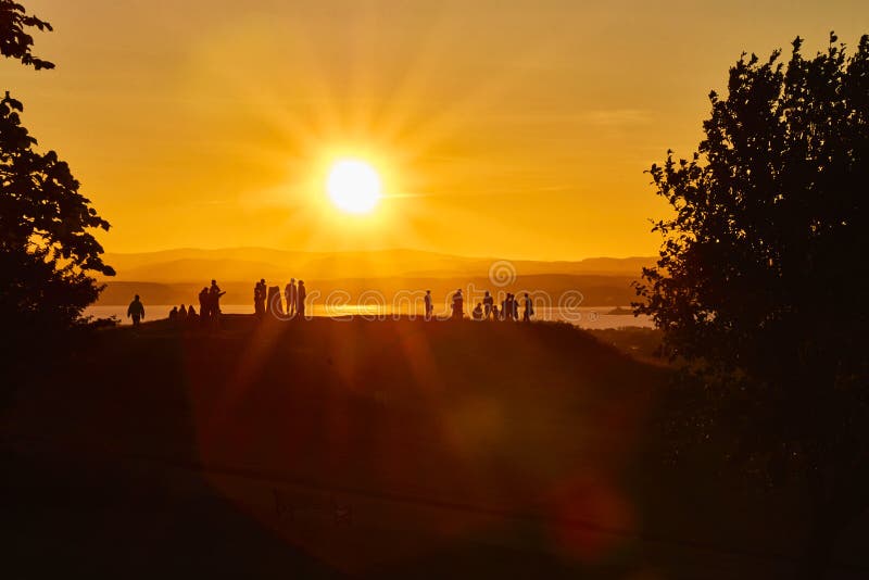 Human Silhouettes Standing on a Hill in Front of an Orange Sunset ...
