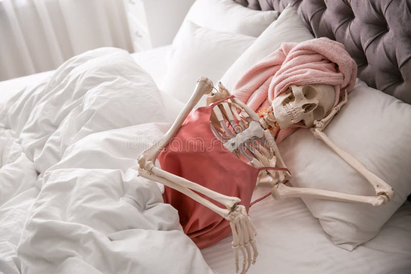 Human Skeleton in Silk Pajamas and Towel Lying on Bed Stock Photo ...