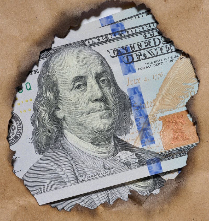 A Hundred Dollar Bill Peeks Out from a Hole in the Burnt Paper Stock ...