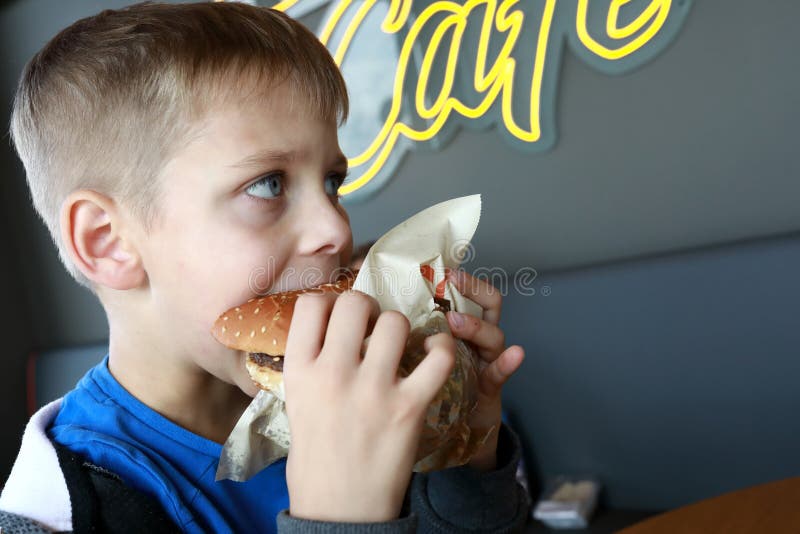 Hungry child biting burger stock image. Image of bite - 229560013