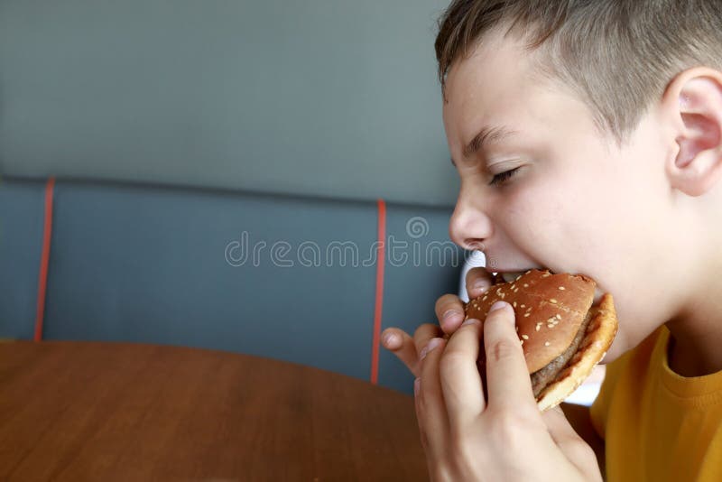 Hungry child eating burger stock photo. Image of bread - 229560016