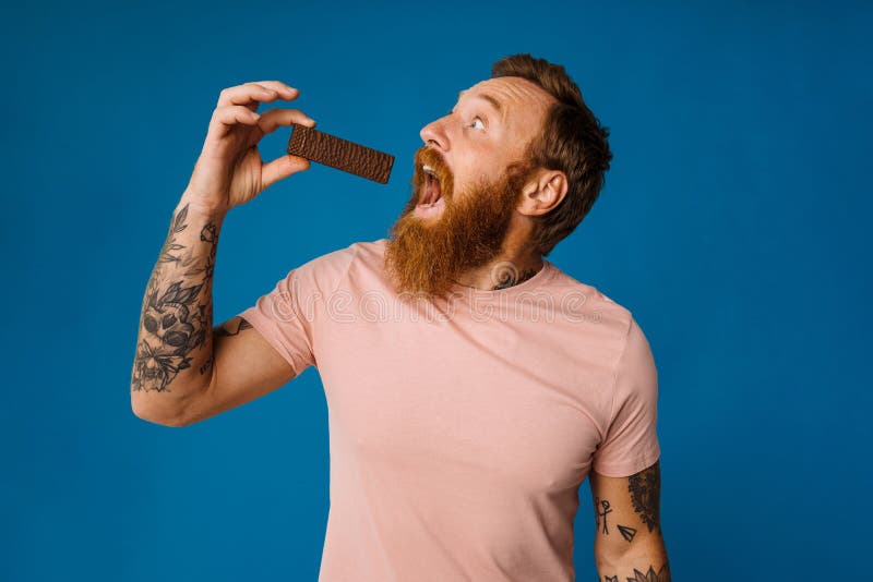 Hungry Man Eating Candy Bar Isolated Over Blue Background Stock Photo ...