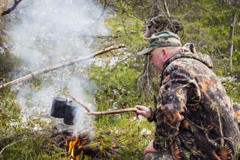 Hunter with Gun at Campfire in Forest during Hunting Season. View from ...