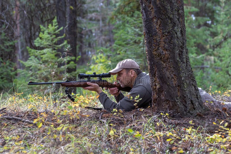 Hunter with Rifle Lies Behind Tree on the Ground. Stock Photo - Image ...