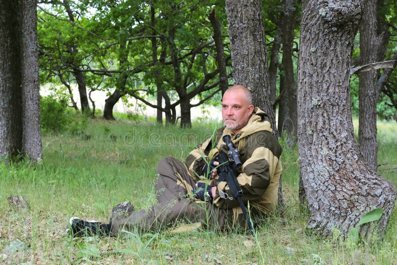 A Hunter Man with a Firearm Sits in a Forest Under a Tree. Hunting ...