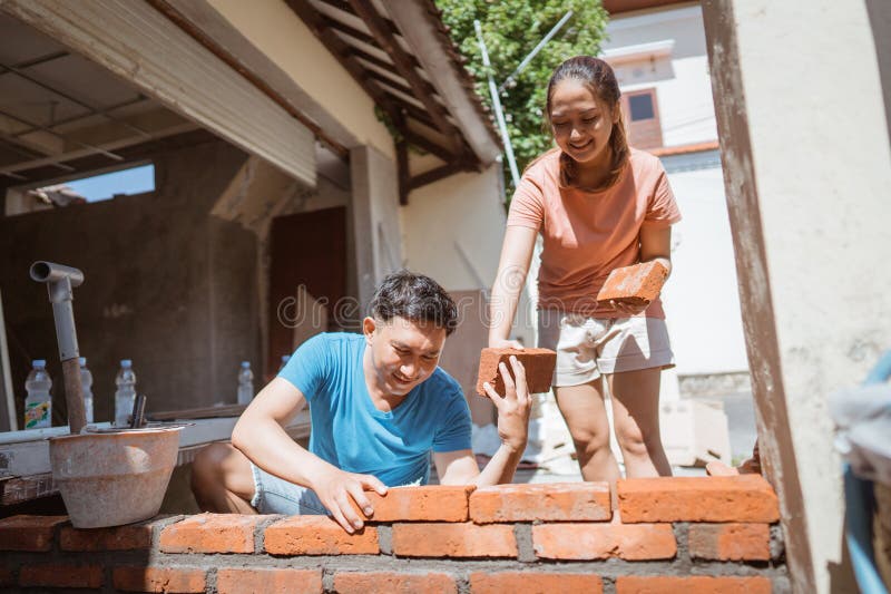 Husband Laying Bricks and Wife Helping To Provide when Making a Wall ...