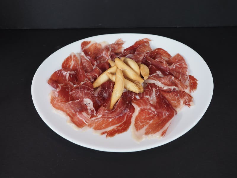 Iberico Ham with Garlic Served in a Dish Isolated on Dark Background ...