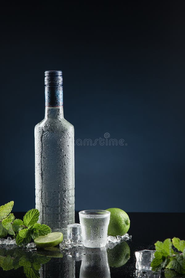 Ice-cold Bottle of Vodka with Shot Glasses on Dark Blue Background with ...