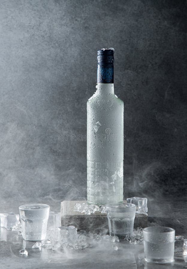 Ice-cold Bottle of Vodka with Shot Glasses on Gray Background with Copy ...