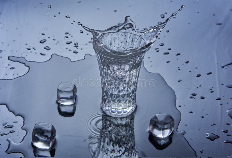 Ice Cubes Splashing into Glass of Water on Wet Background with Water ...