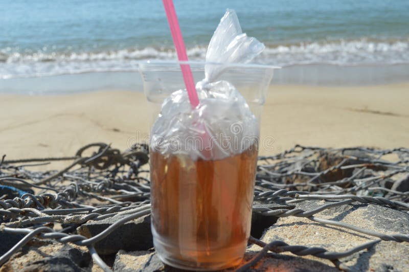 Ice Tea in a Plastic Cup with Red Straw on Stone. Beach Refreshments ...