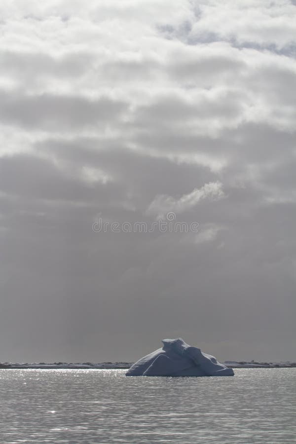 Iceberg in the Ocean, Backlit on a Cloudy Day Stock Photo - Image of ...
