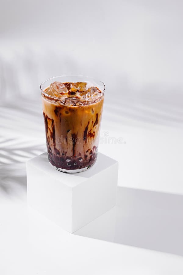 Iced Coffee with Chocolate Syrup Standing on White Cube with Palm Leaf ...