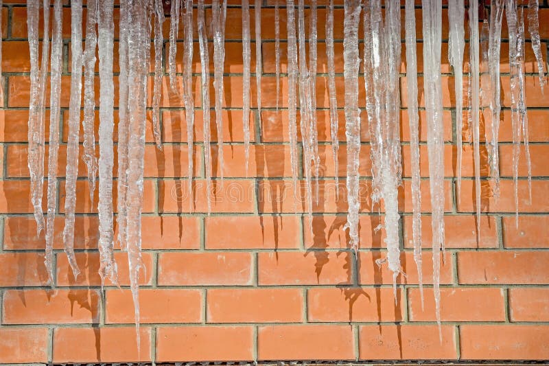 Icicles of Ice Hang Against the Red Brick Wall of the Building ...