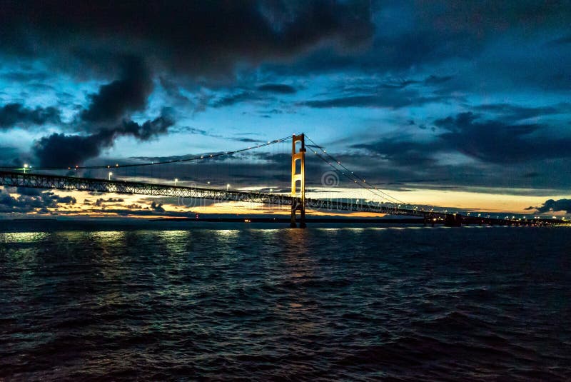 Illuminated Bridge Over the River Under the Dark Cloudy Sky at Night ...
