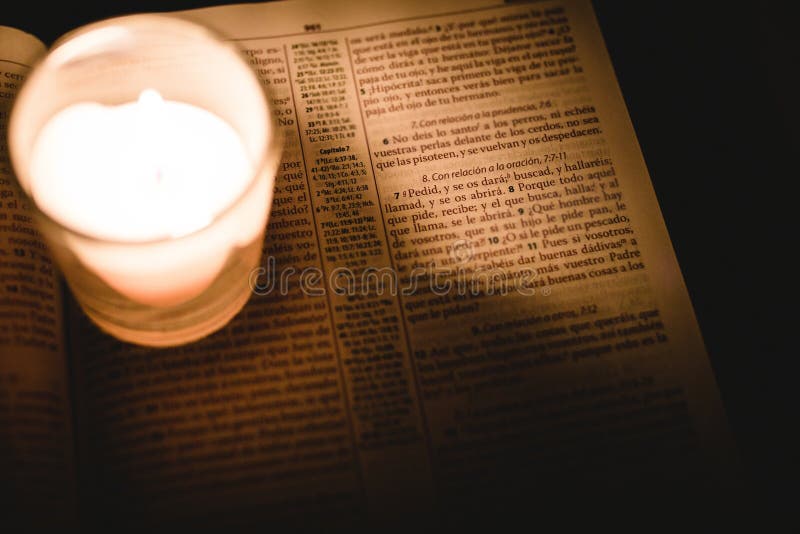 Illuminated Candle in a Jar on a Bible Book Written in Spanish in a ...