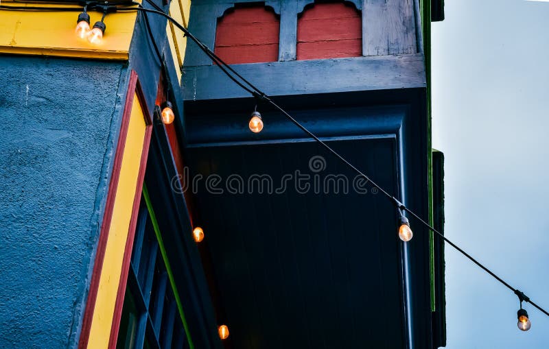 Illuminated Edison Light Bulbs on Wire Against Blue Painted Building ...