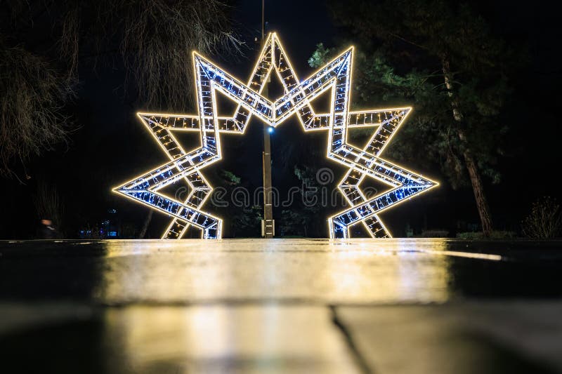 Illuminated Geometric Star Structure in Night Park with Reflective Wet ...