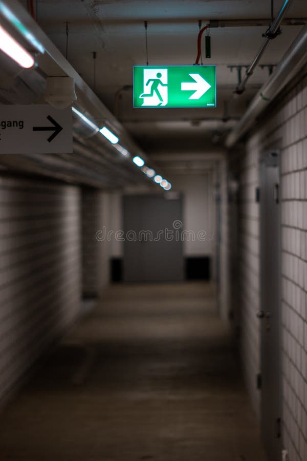 Illuminated Green Exit Sign Hanging from the Wall in and Underground ...
