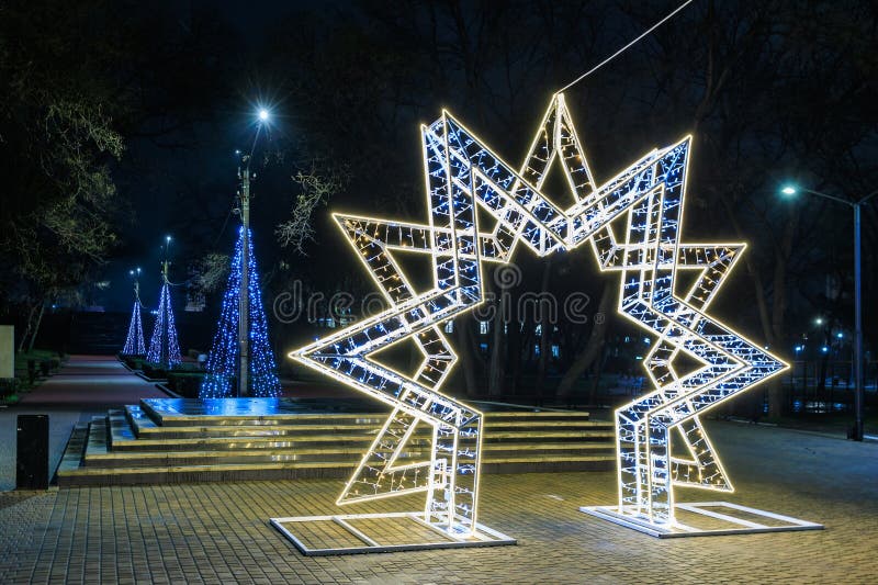 Illuminated Star Sculpture in Park with Twinkling Blue Trees at Night ...