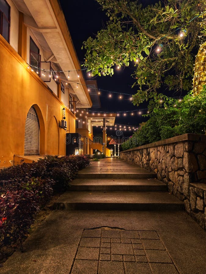 Illuminated Walkway with String Lights and Urban Architecture at Night ...
