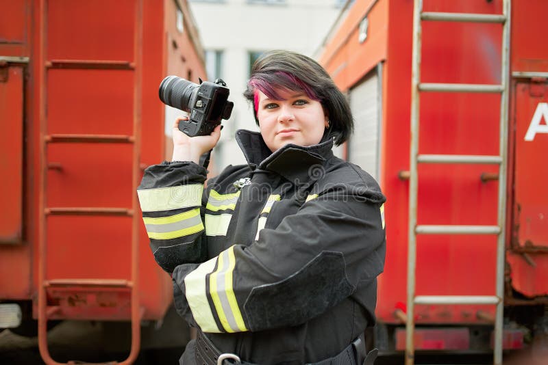 Image of Brunette Firefighter with Camera at Hand Standing Next To ...