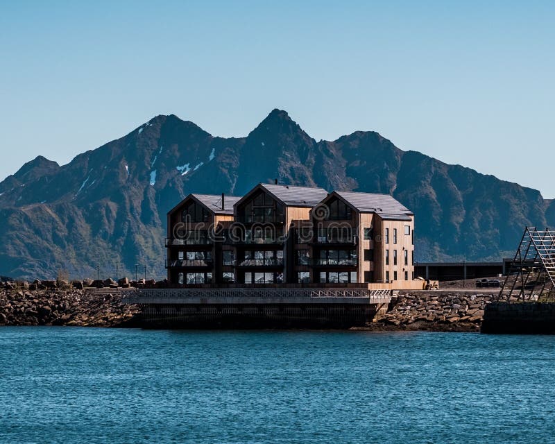 Image of a Building in Front of a Water Surface with Mountains on the ...