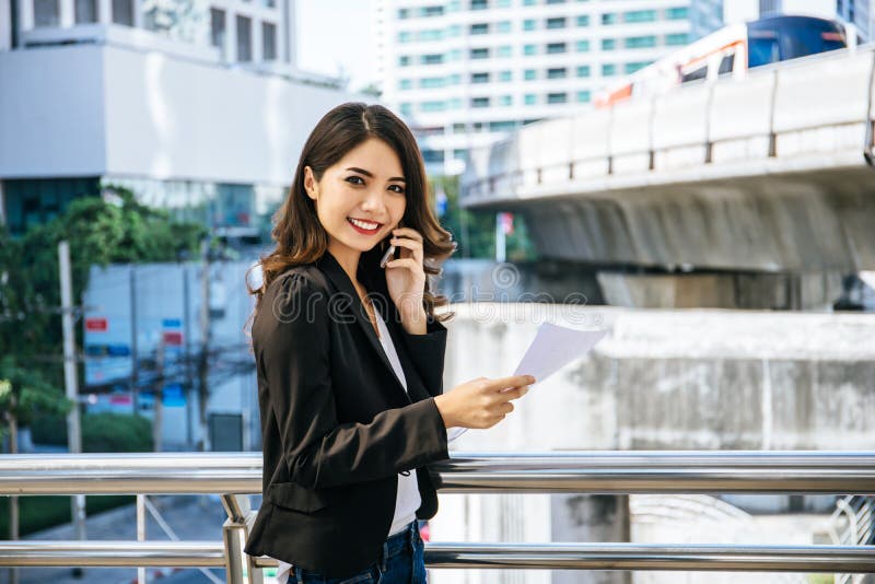 Image of Busy Female Calling on the Phone and Reading Document while ...