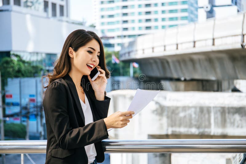 Image of Busy Female Calling on the Phone and Reading Document while ...