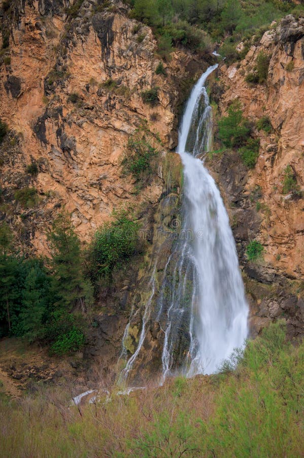 The Image Features a Tall, Cascading Waterfall Flowing Down a Rugged ...