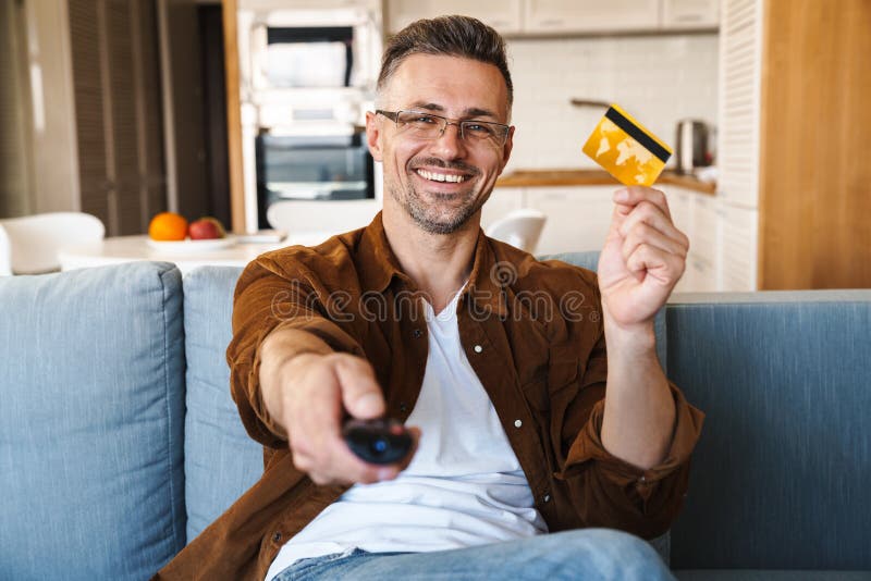 Image of Handsome Smiling Man Holding Credit Card while Watching Tv ...