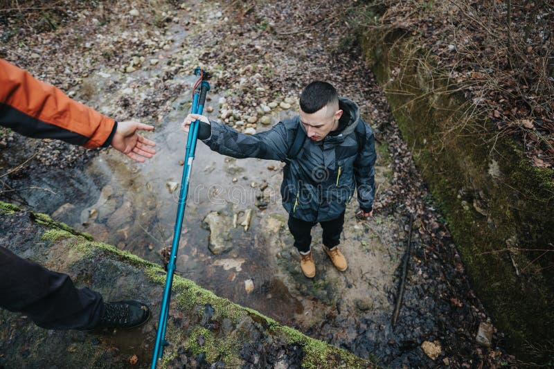 A Hiker Receiving a Helping Hand while Crossing a Rocky and Mossy ...